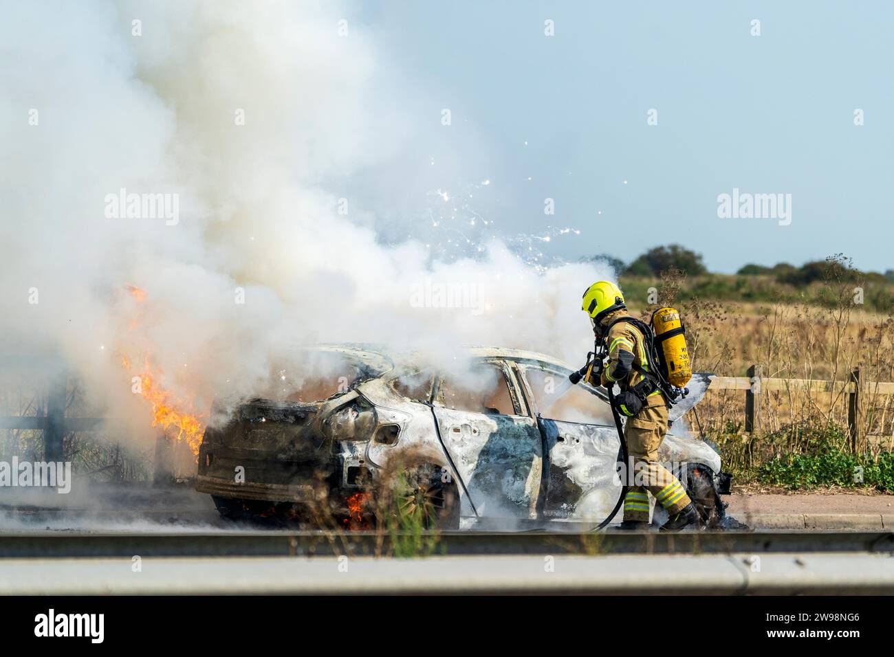 Fireman putting out a car fire on the A299, Thanet way. Spraying water ...