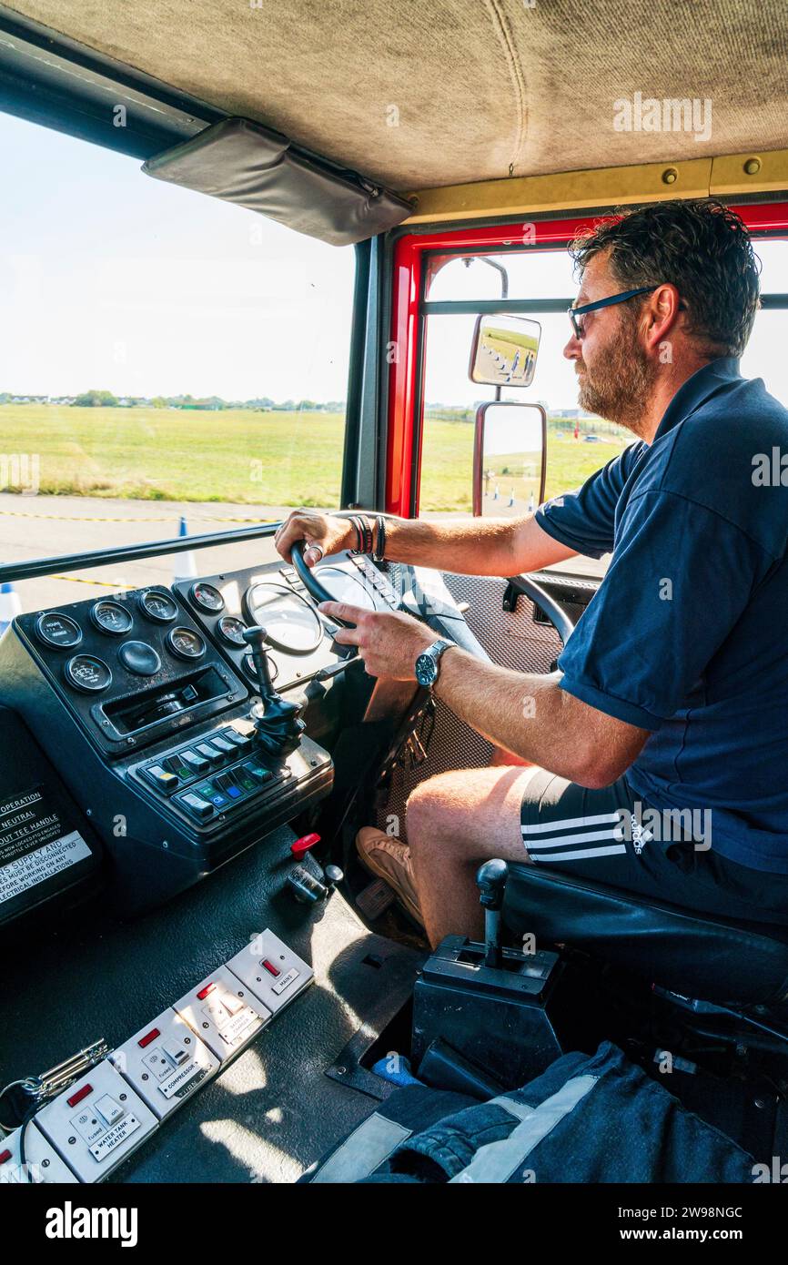 Man driving fire engine. Interior side view of man in t shirt and ...