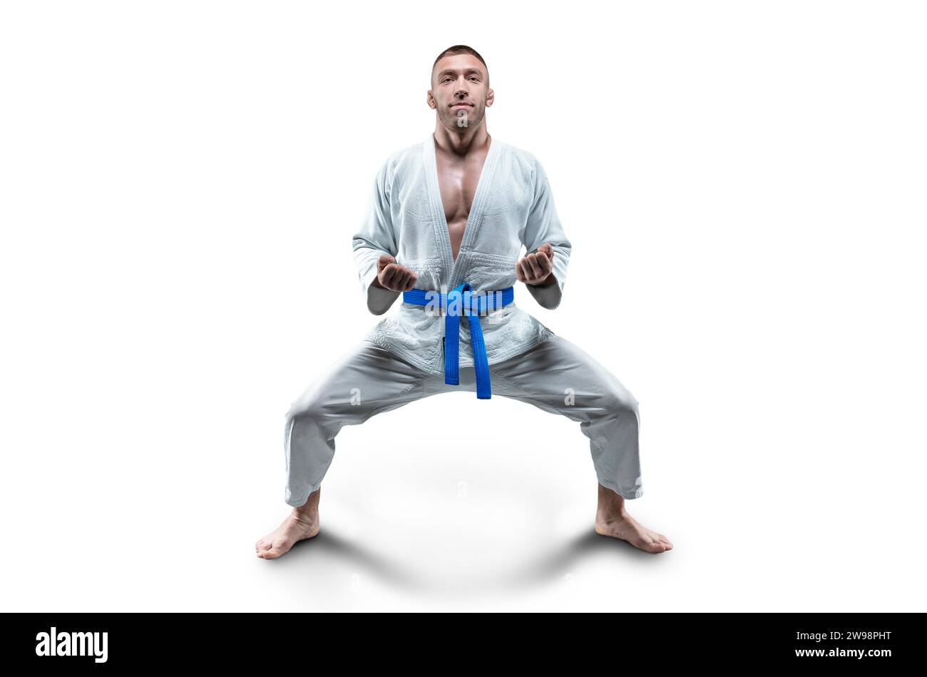Athlete in a kimono with a blue belt stands in a fighting position ...