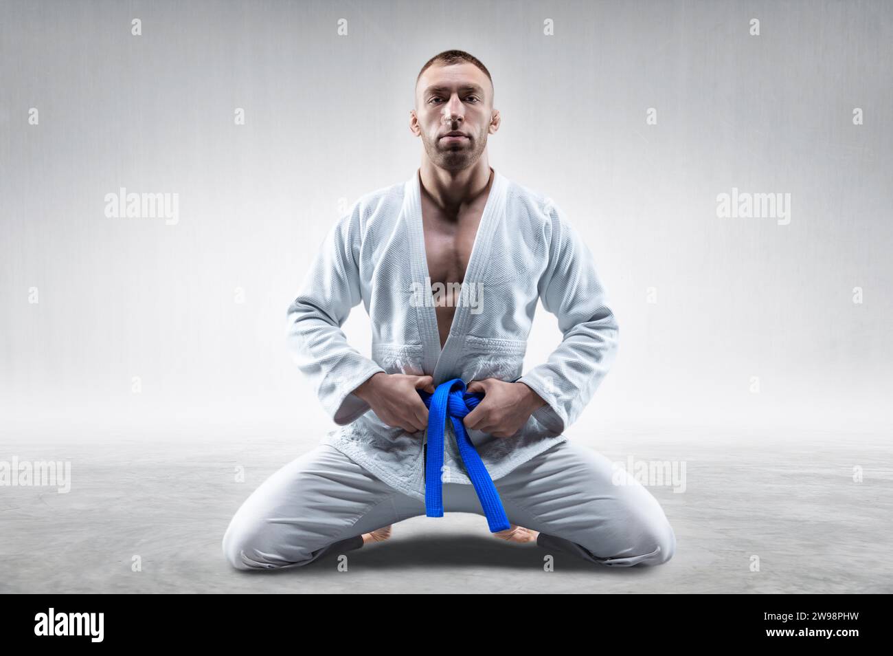 Athlete in a kimono with a blue belt sits and waits for the opponent ...