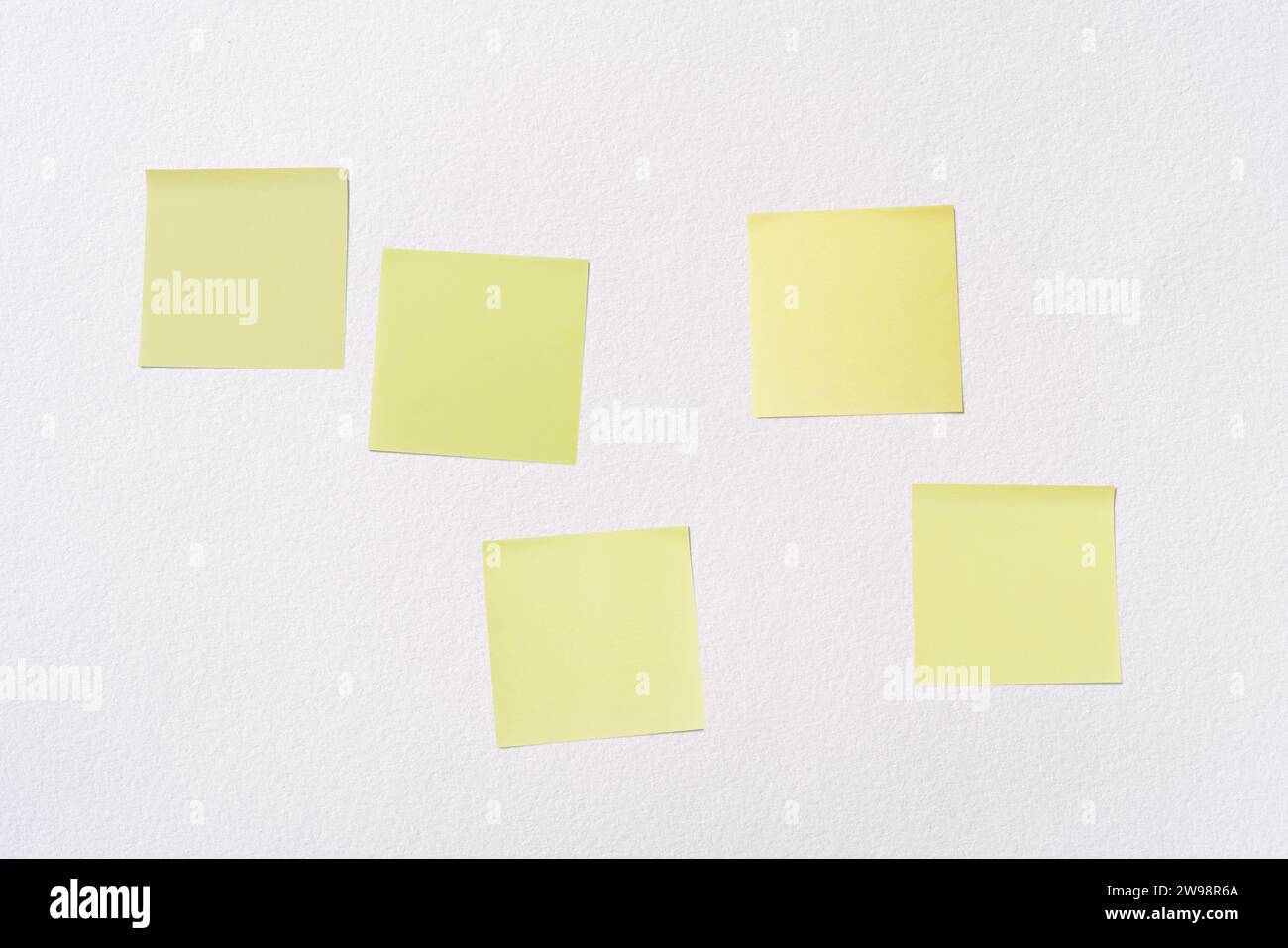 Five blank yellow Post-it notes (sticky notes) on a white paper ...