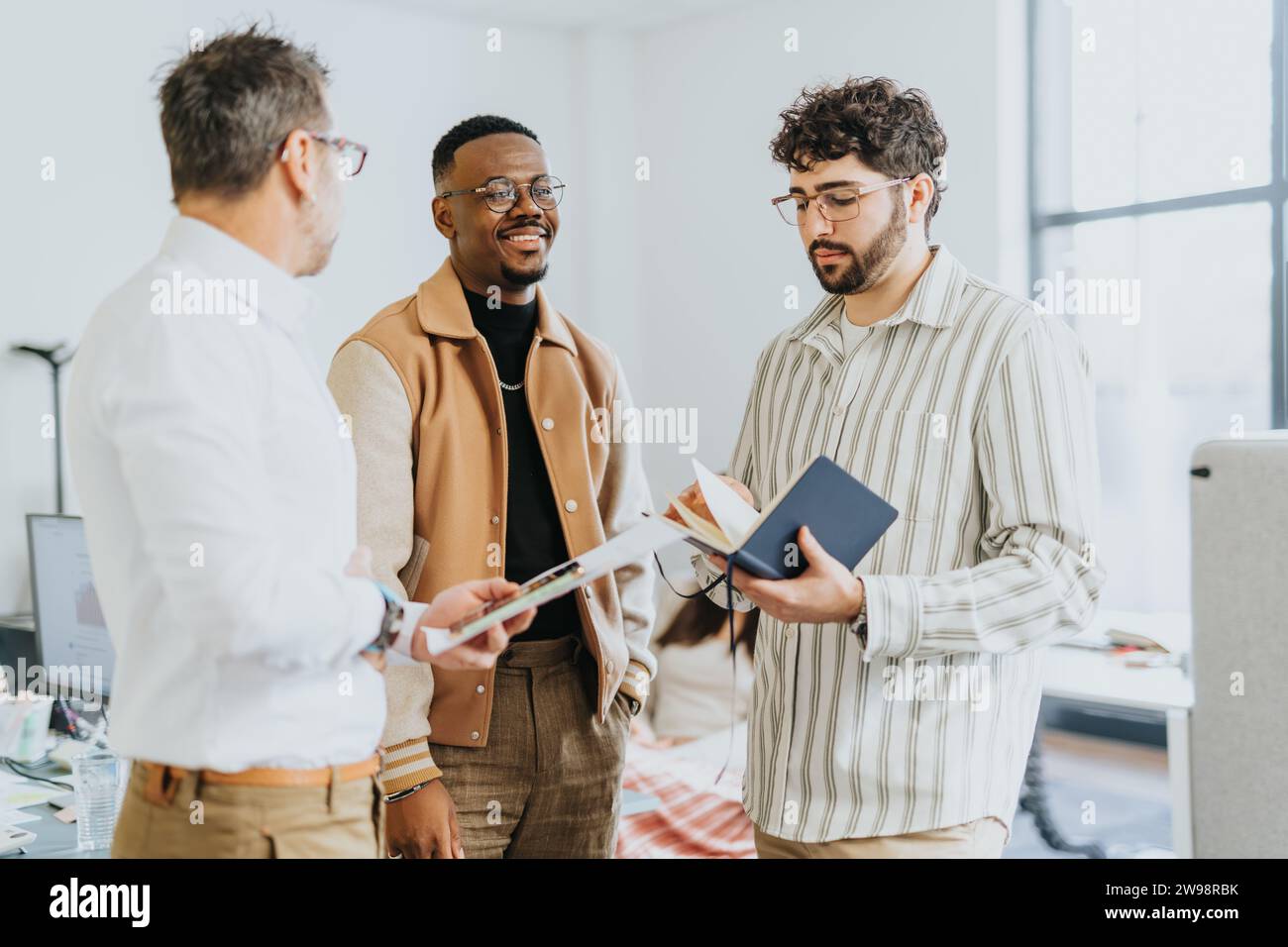 Diverse coworkers collaborate in a modern office, strategizing and ...
