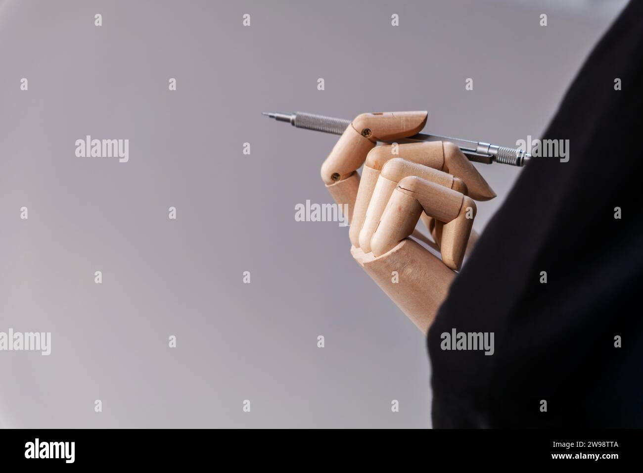 Hold a metallic pencil wooden puppet hand Stock Photo - Alamy