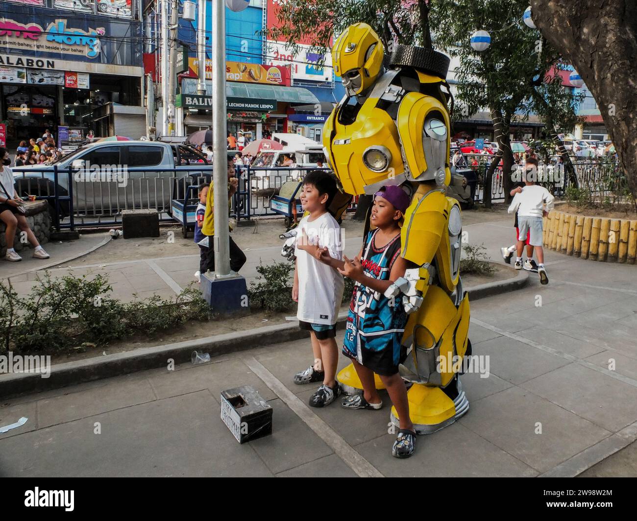 Malabon City, Philippines. 25th Dec, 2023. Two boys take a picture with the Bumblebee. A meet ...