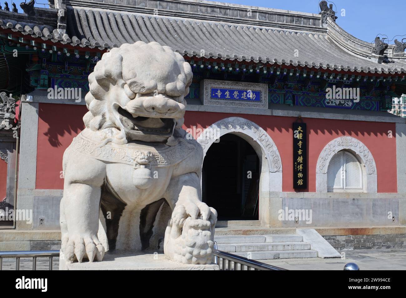 An outdoor sculpture of a majestic lion stands in front of a Chinese ...