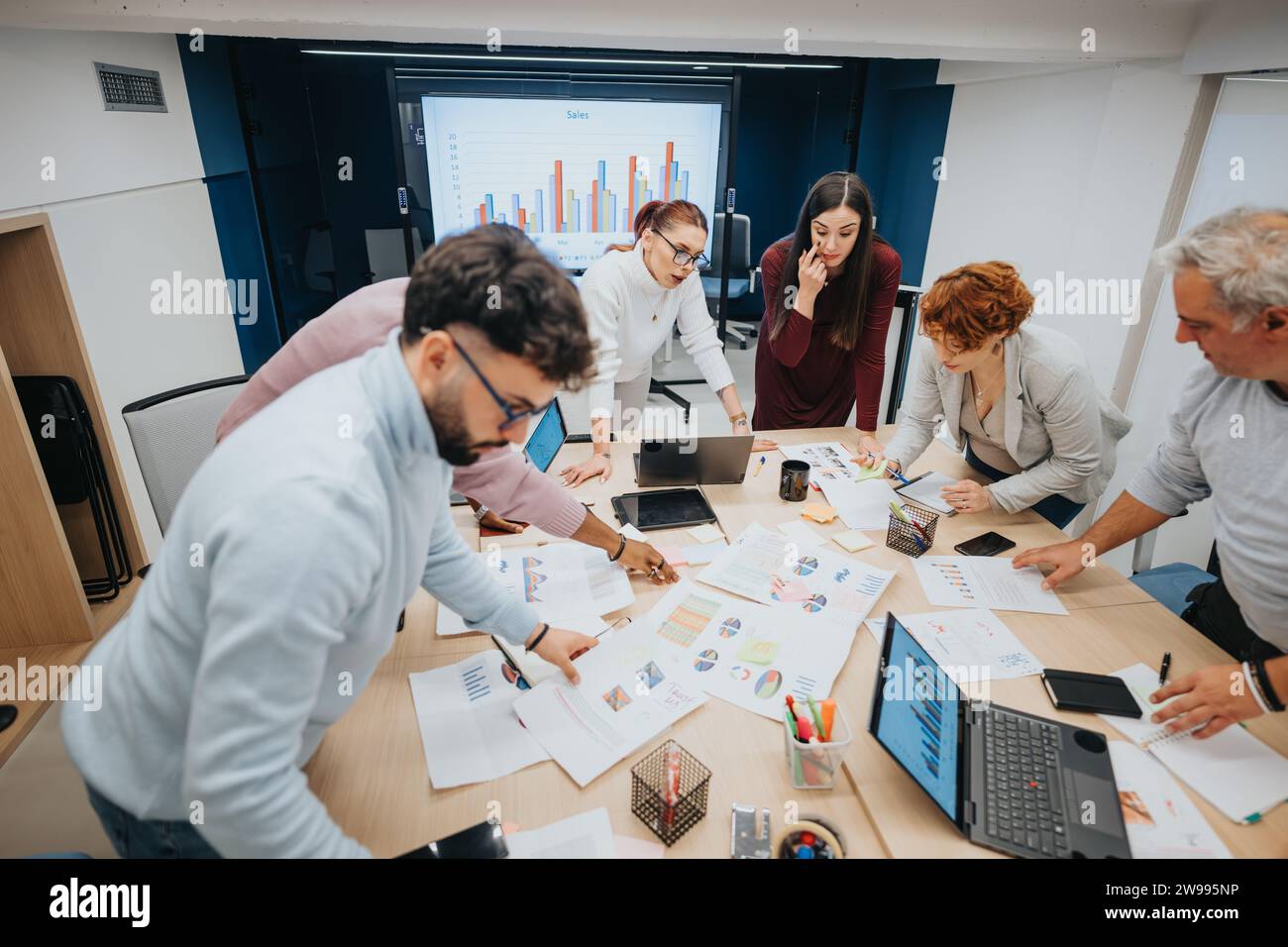 Multi generational business team collaborating, analyzing stats ...