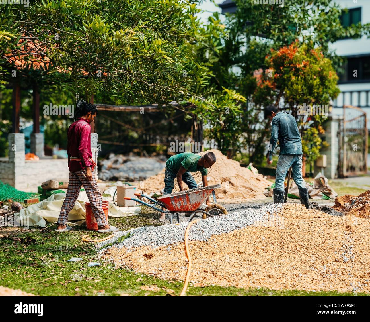 Men mixing concrete with shovel on the floor by hand at a house ...
