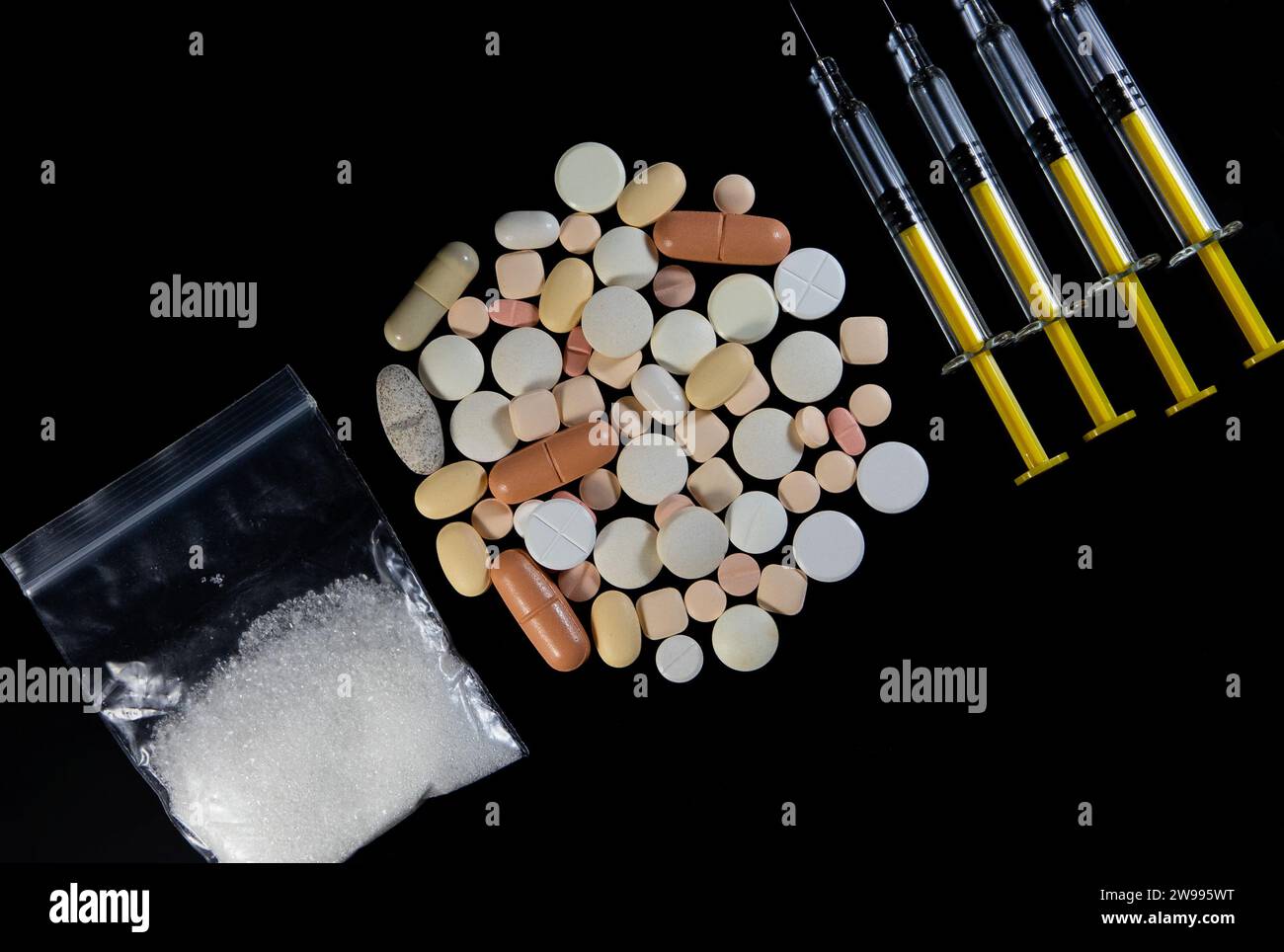 The pills, syringes and drugs on a black background, symbolizing the ...