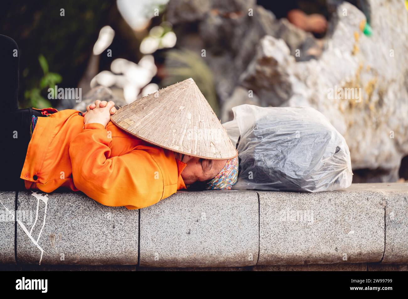 A homeless male with a rice hat sleeping in a park in Vietnam Stock ...