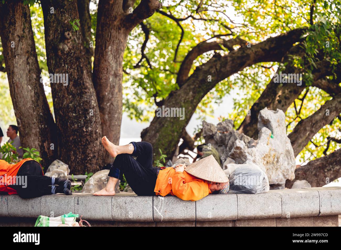 A homeless male with a rice hat sleeping in a park in Vietnam Stock ...