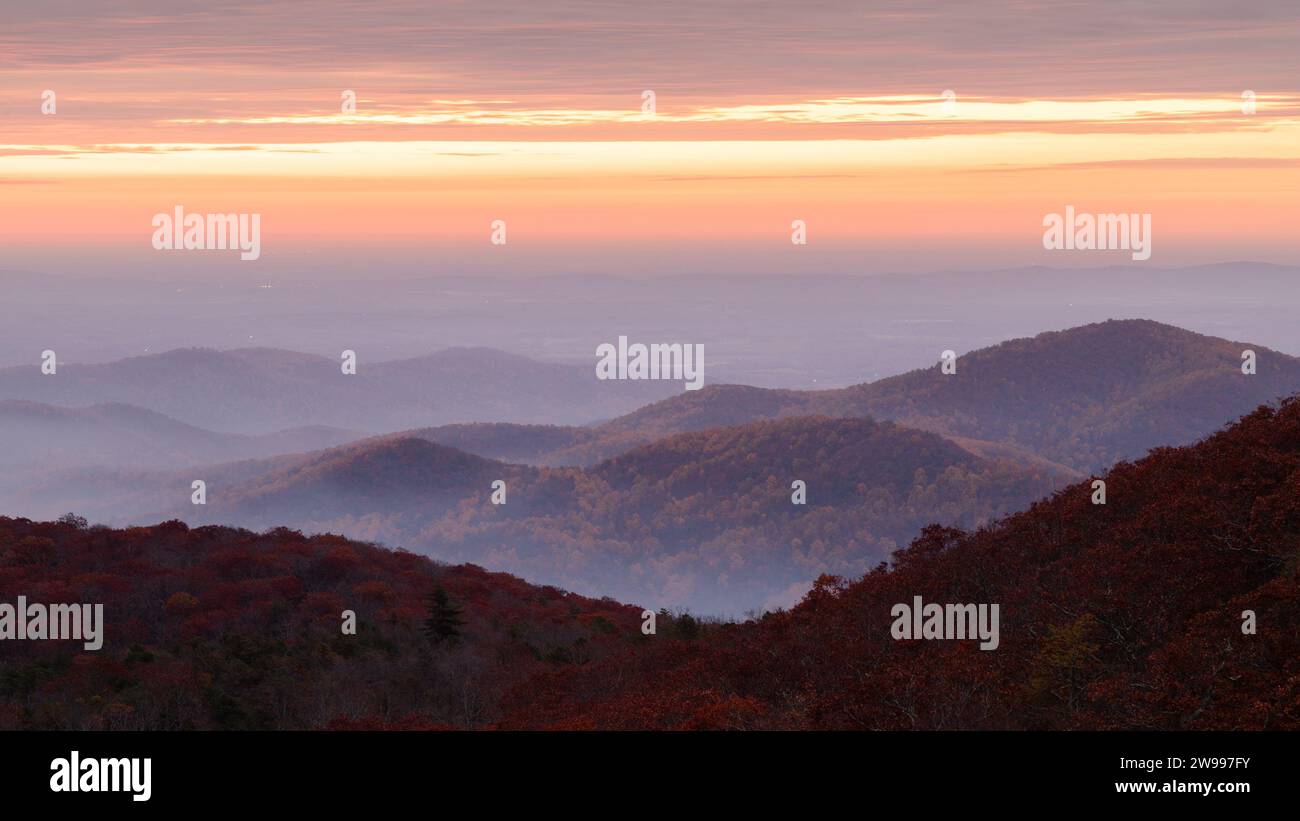 Colorful sunrise behind rolling mountains with red and orange fall ...