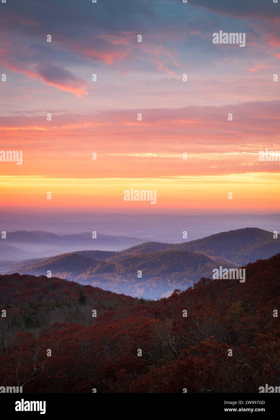 Colorful sunrise behind rolling mountains with red and orange fall ...