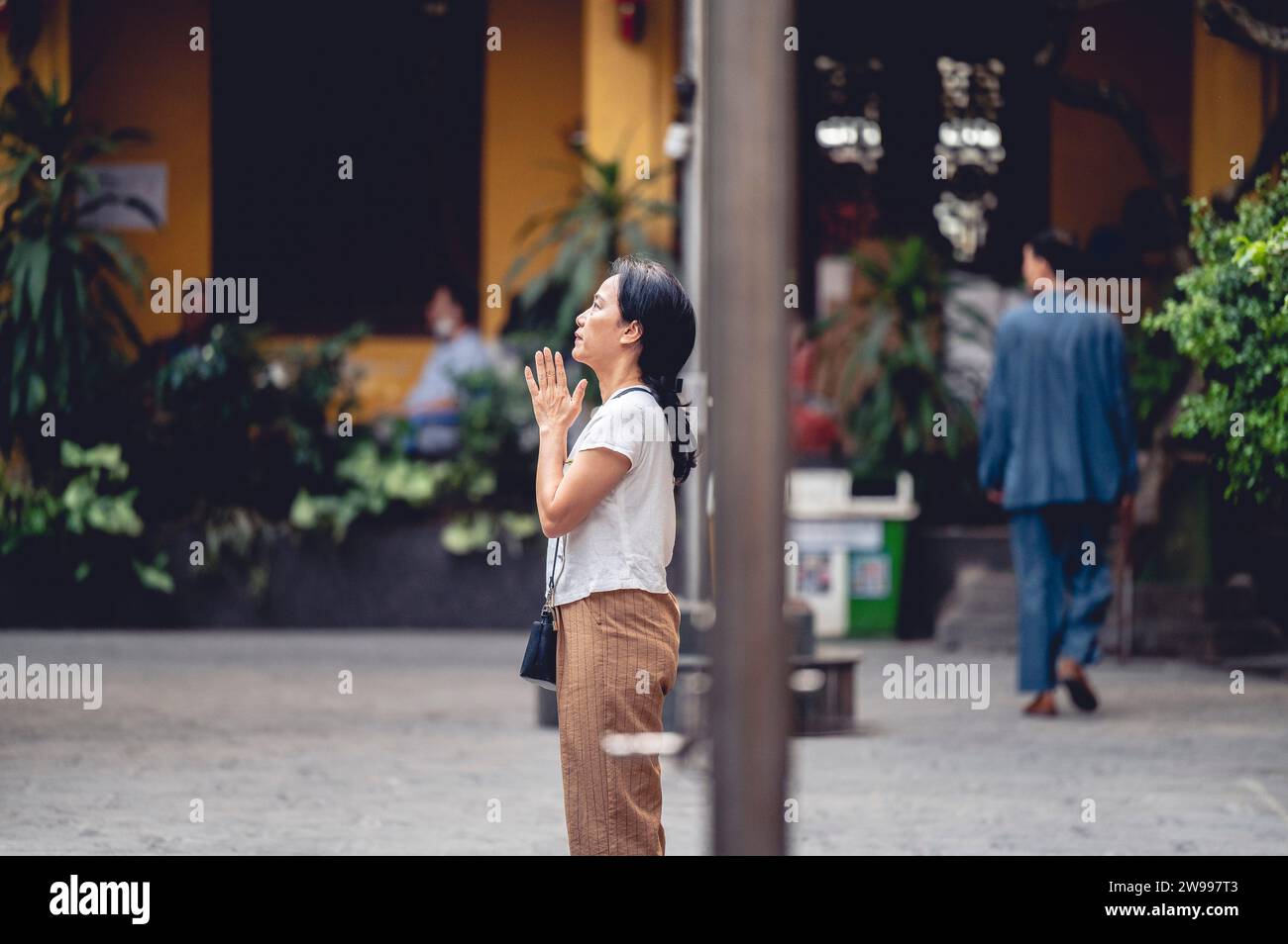 A Buddhist worshiper praying at the altars of Buddhist idols with ...