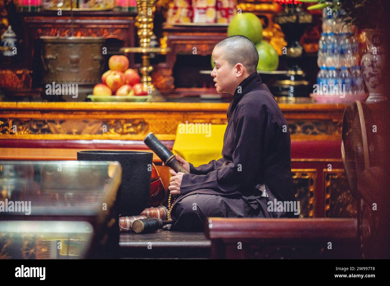 A Buddhist monk praying at the altars of Buddhist idols with incense ...