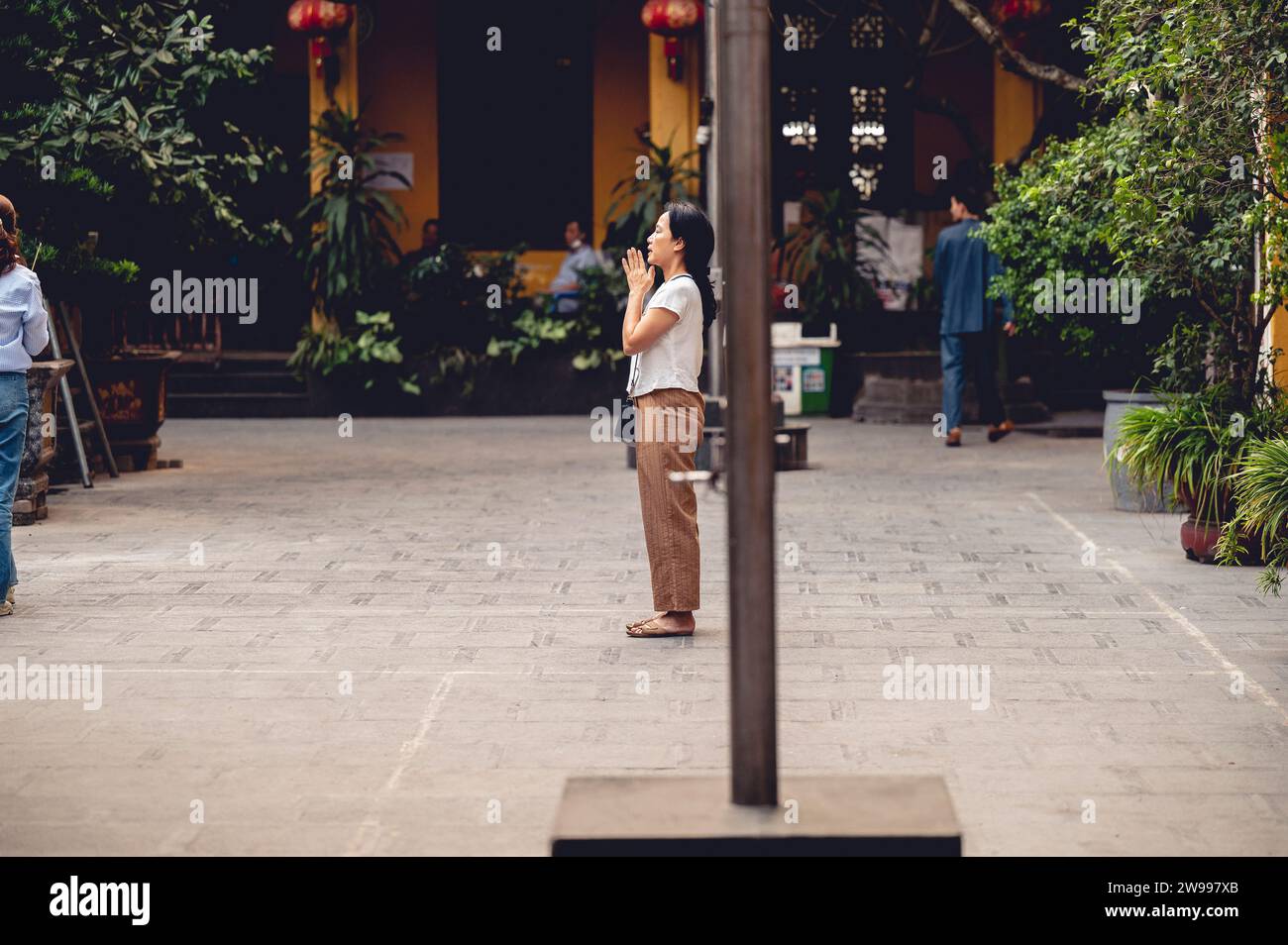 A Buddhist worshiper praying at the altars of Buddhist idols with ...