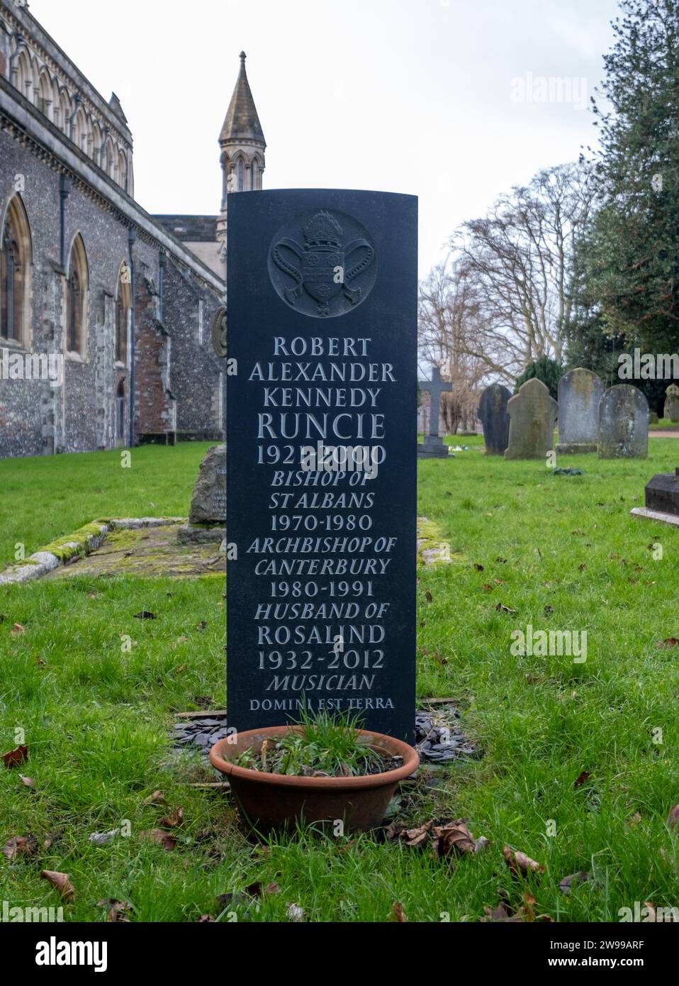 A weathered grey tombstone in a cemetery in front of a historic stone ...