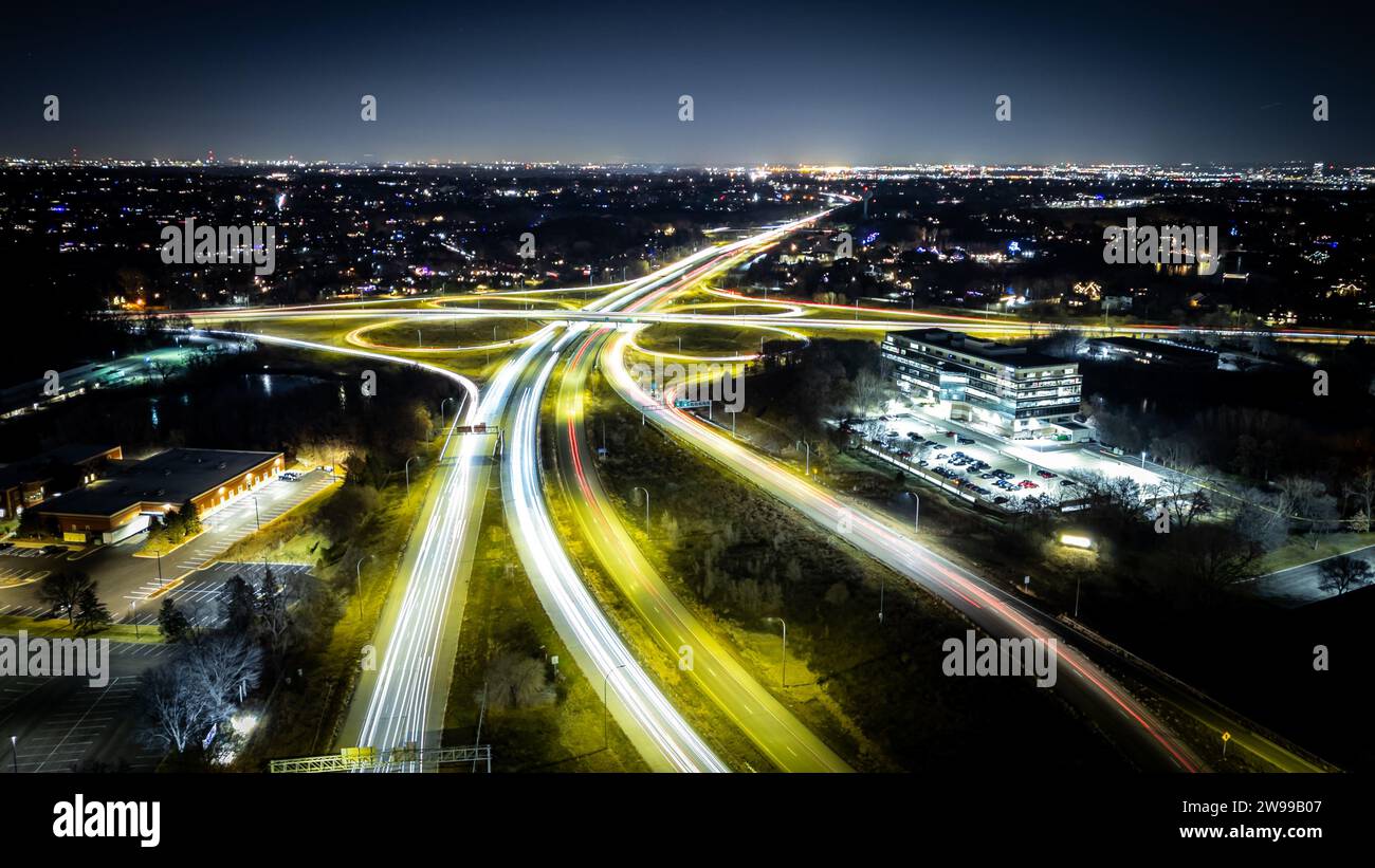 An aerial view of a highway at night, with the sweeping lights of cars ...