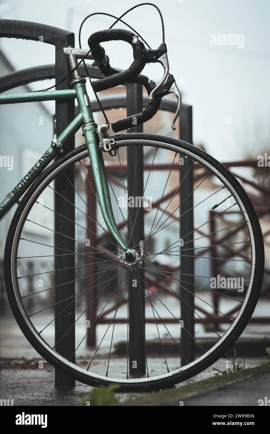 A modern bicycle with a green frame standing upright against a metal ...