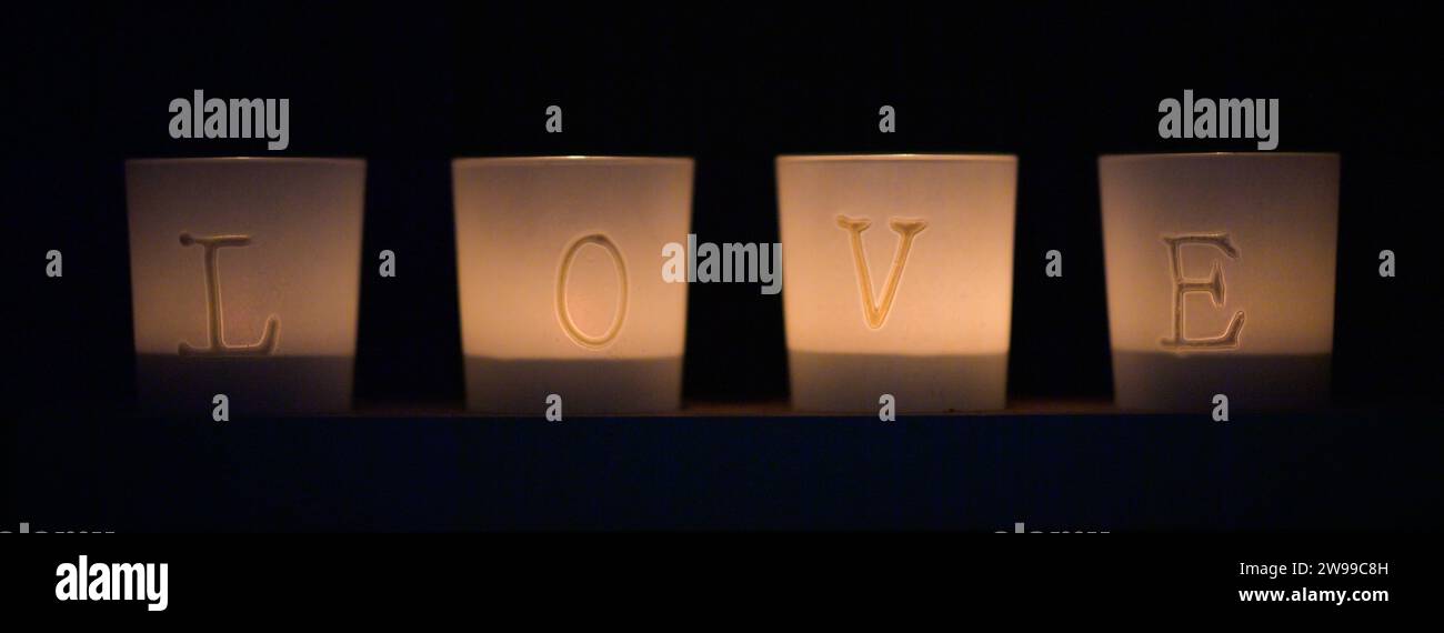 burning white candles arranged in a line to spell out the word 'LOVE ...