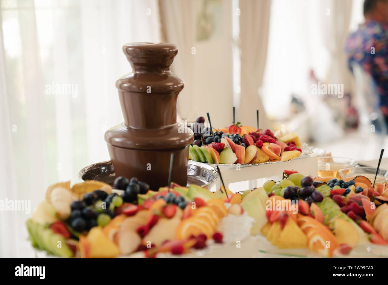 Three chocolate fountains decorated with an assortment of fresh fruit ...