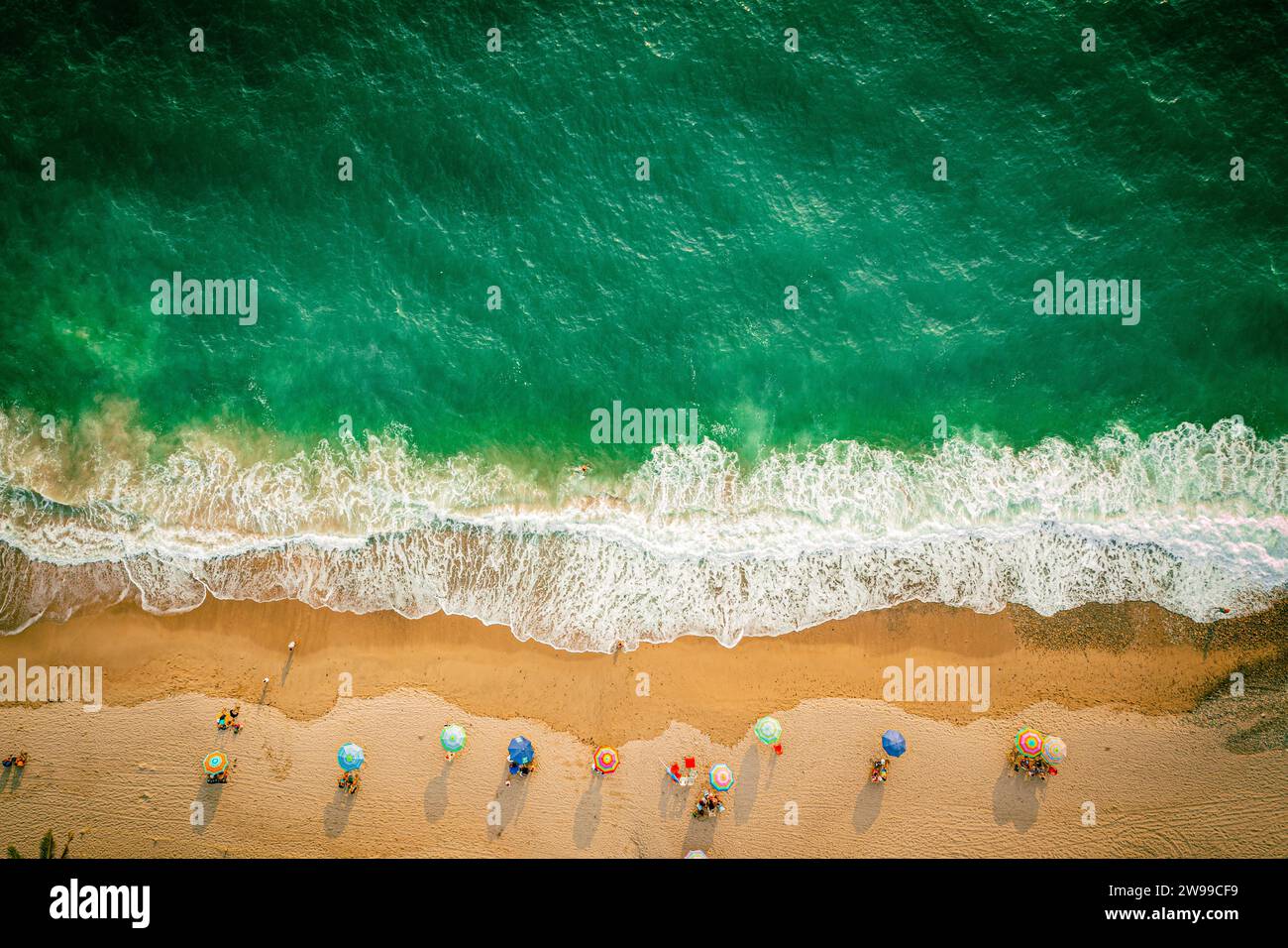Drone top down shot of the beach and colorful ocean with umbrellas ...