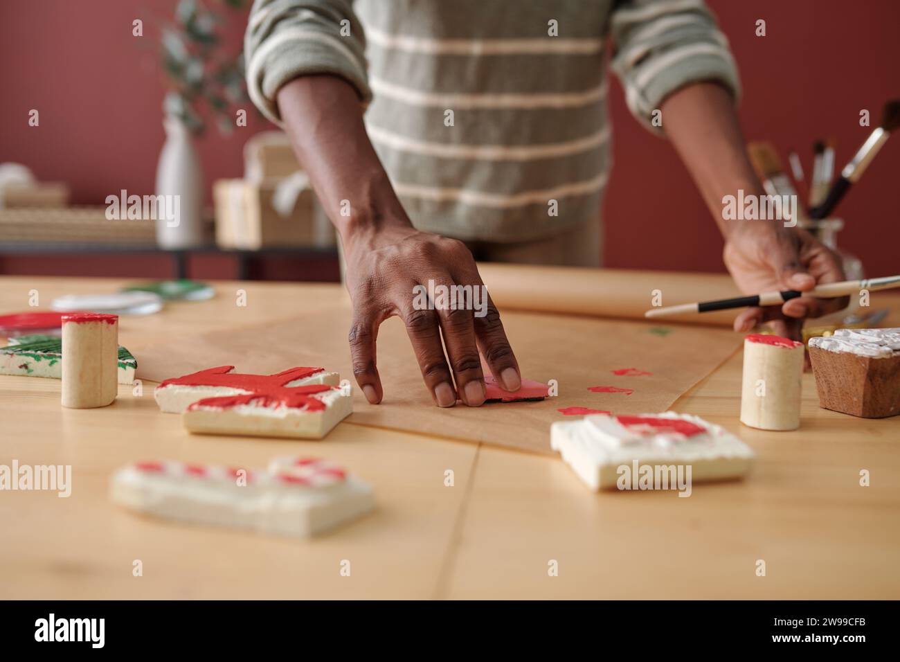Young woman making prints of handmade workpieces while pressing one of ...