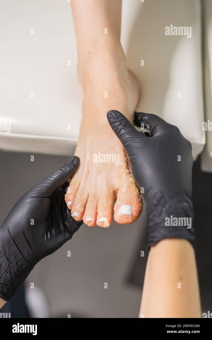 Woman doing foot peeling in pedicure SPA salon. Sugar scrub and relax ...