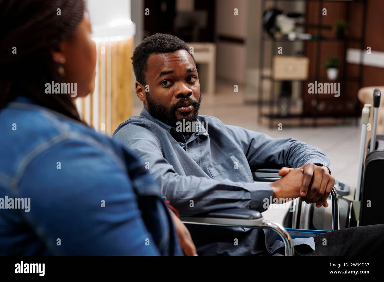 African American man hotel guest with reduced mobility sitting in lobby ...