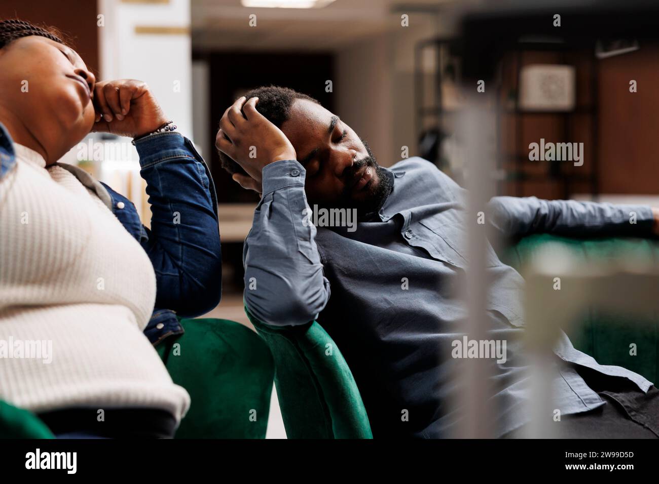 Tired unhappy African American family couple sleep in hotel lobby ...