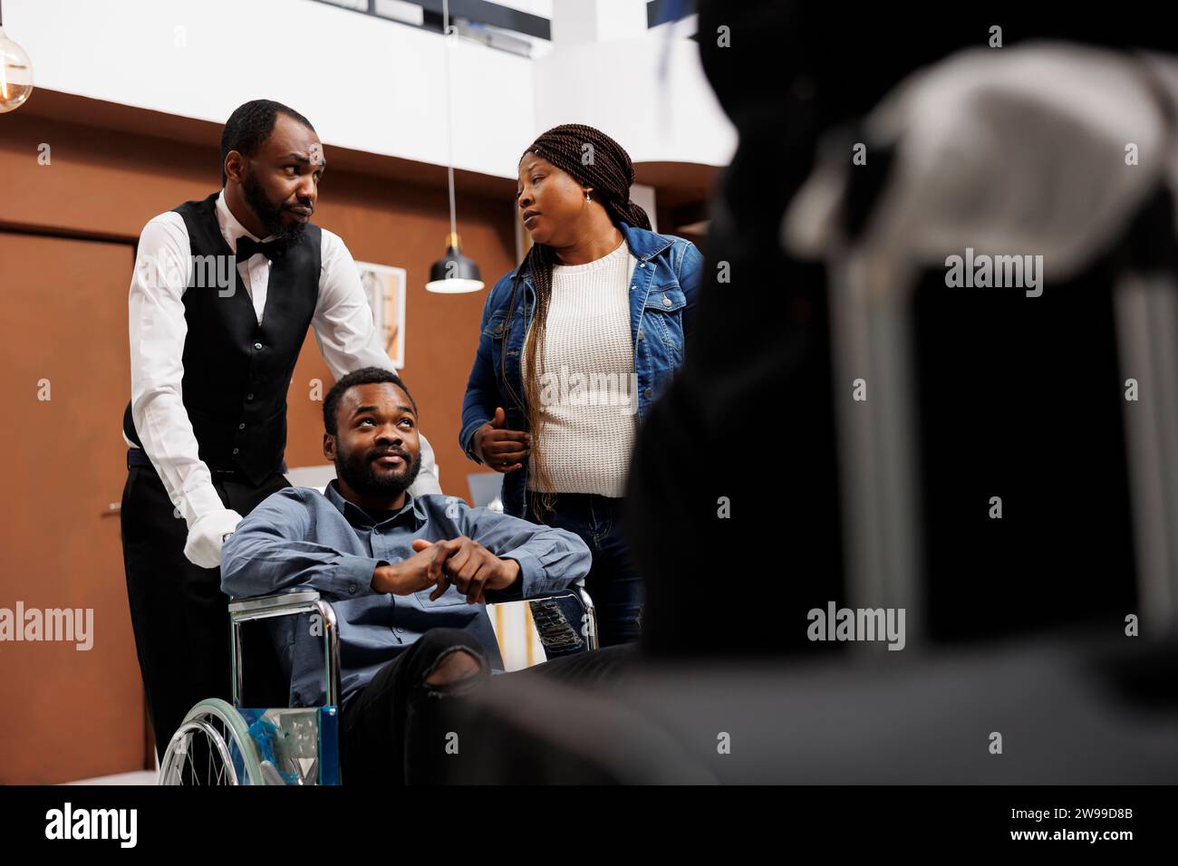 Hotel bellman transferring disabled guest on wheelchair to room, happy ...