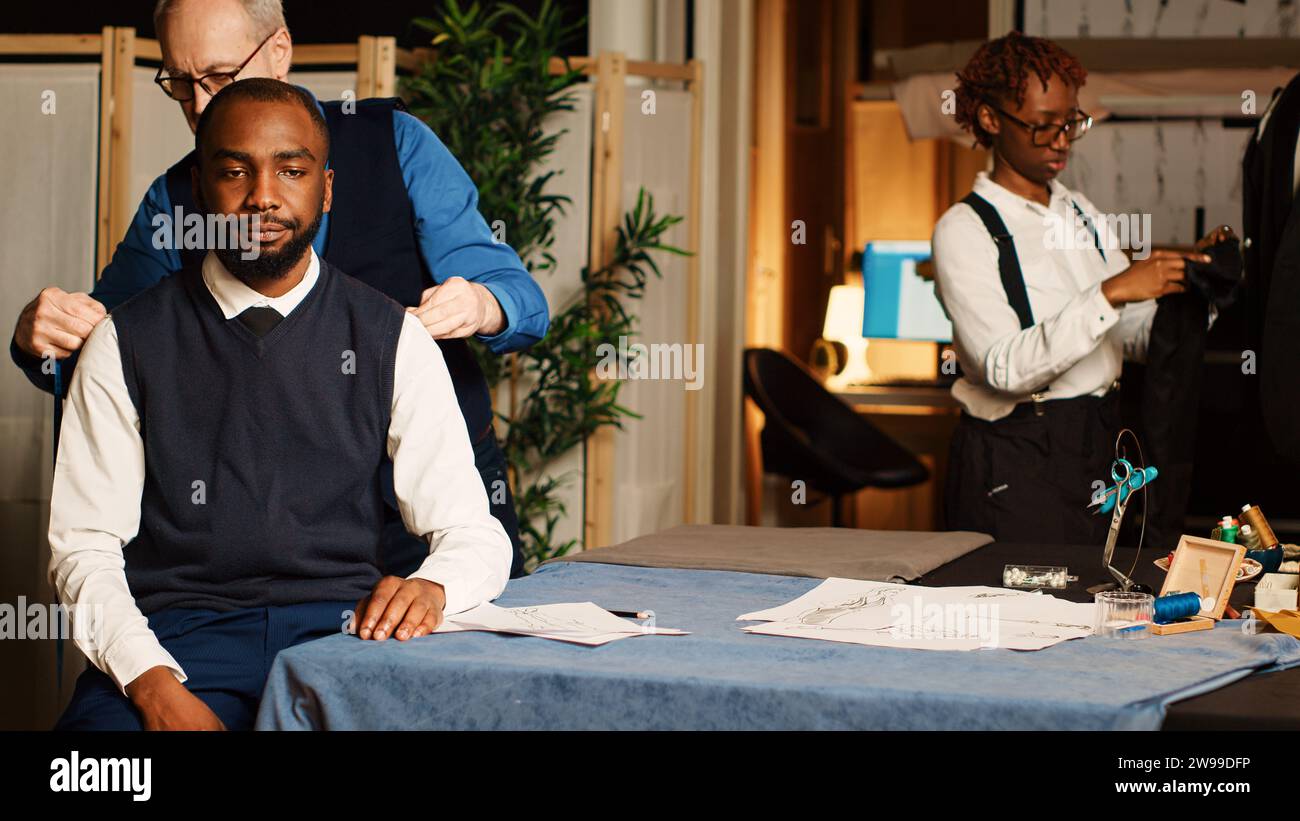 Experienced tailor taking measurements of client to create custom made ...