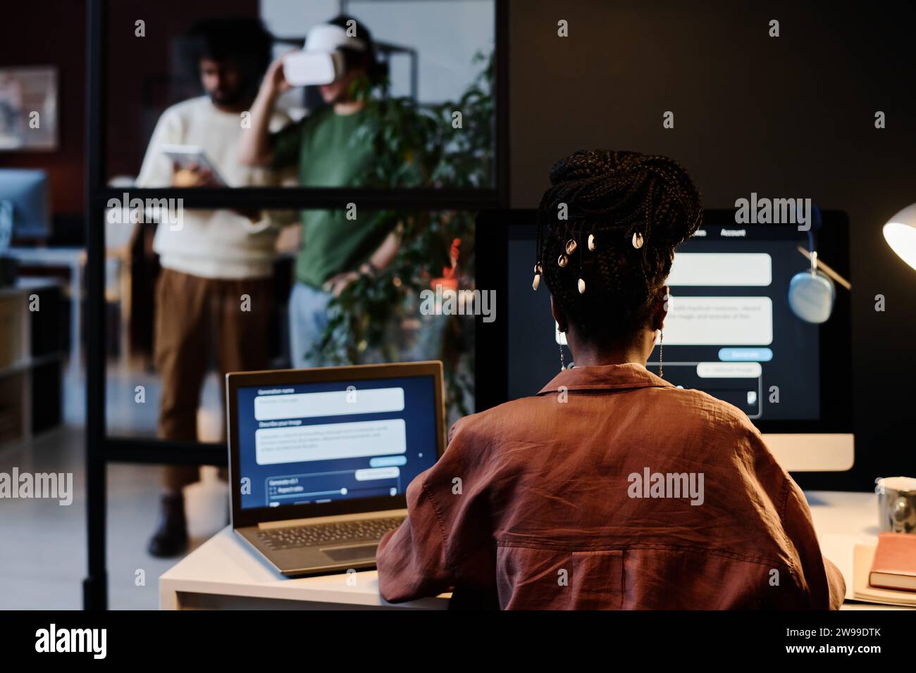 Rear view of young African American female designer sitting in front of ...