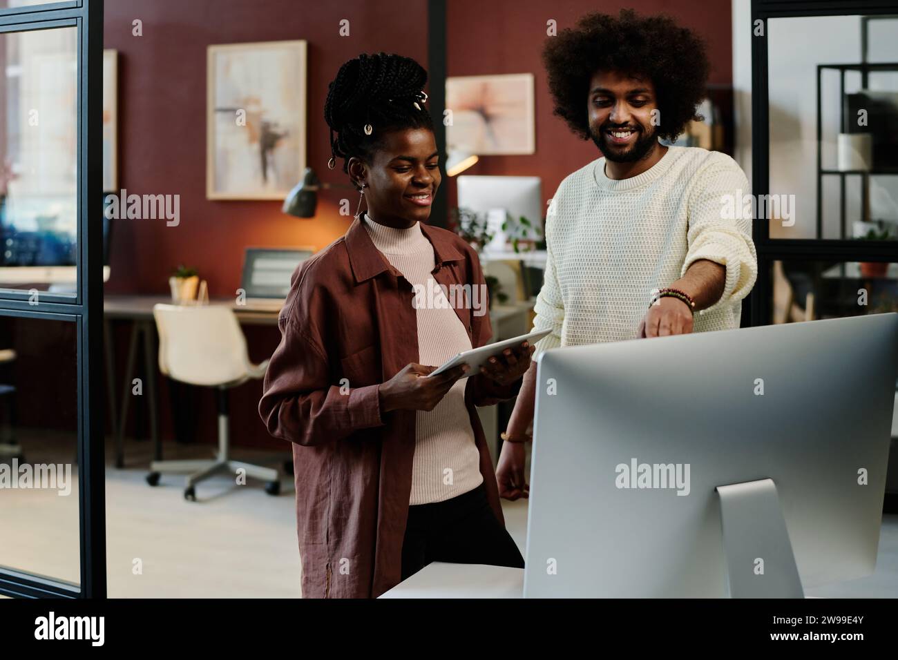 Young smiling man pointing at computer screen during presentation of ...