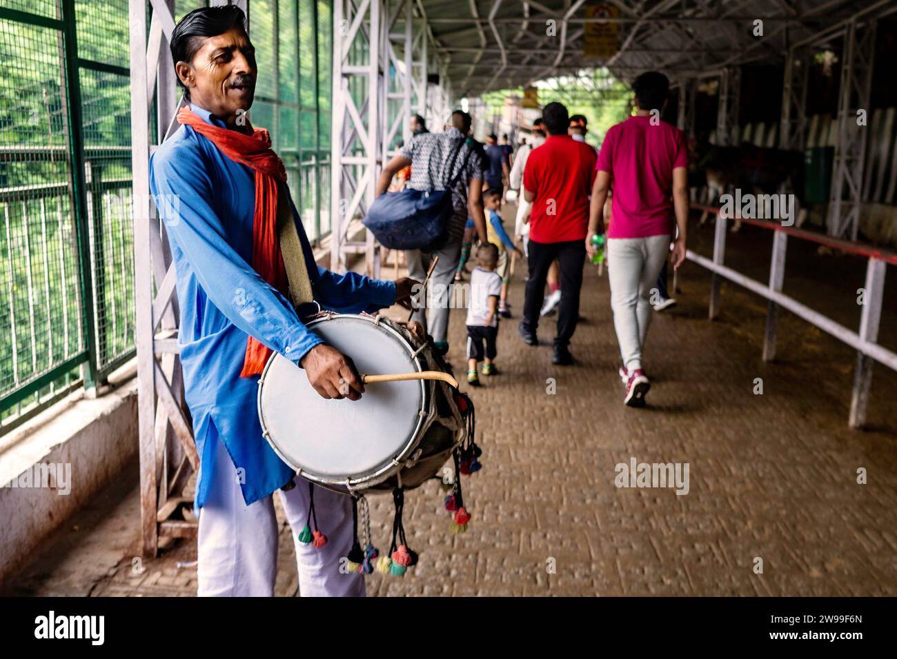 A street performer with a drum standing on a walkway with a crowd of ...