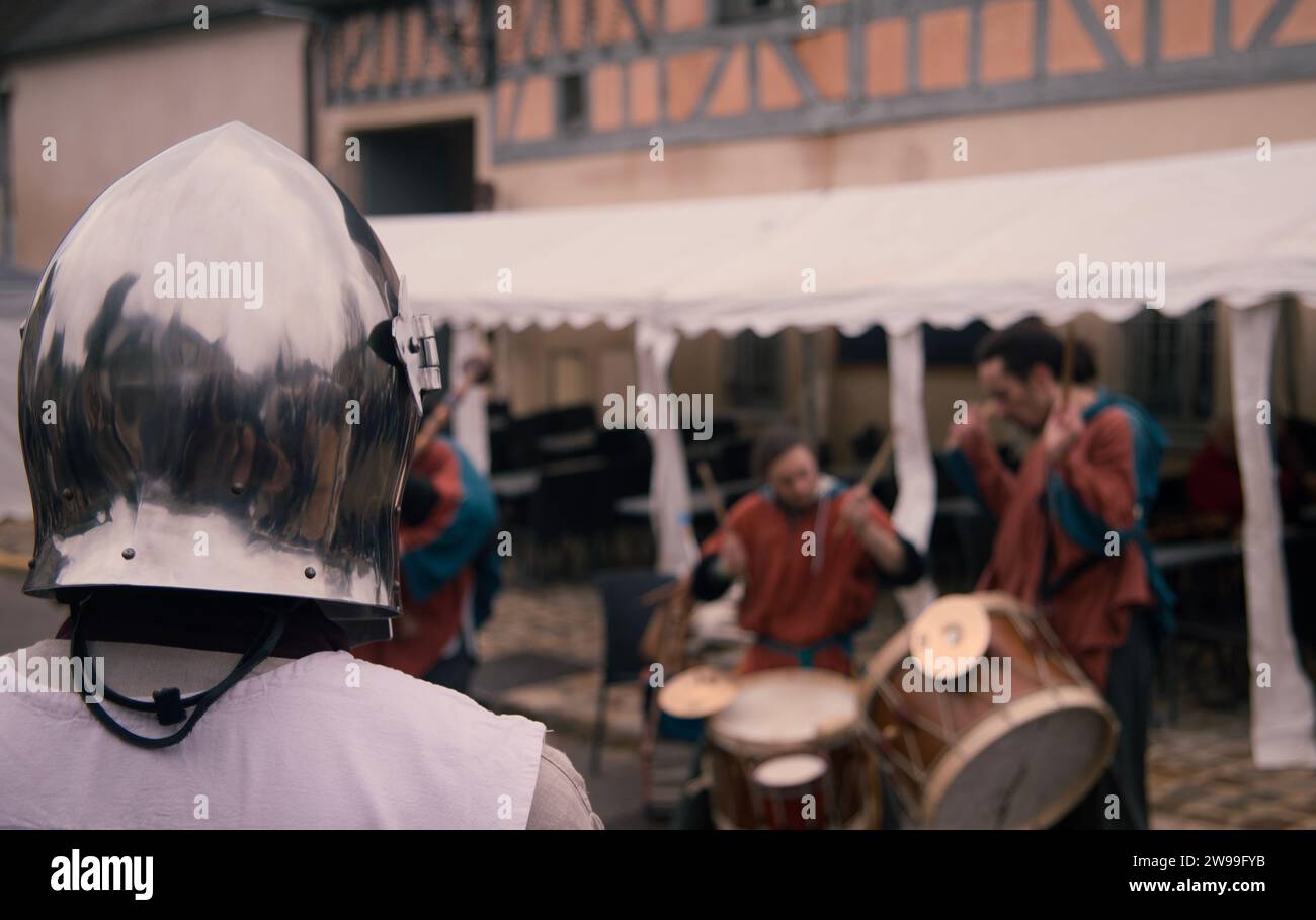 A diverse group of people are gathered in a city street, playing drums ...