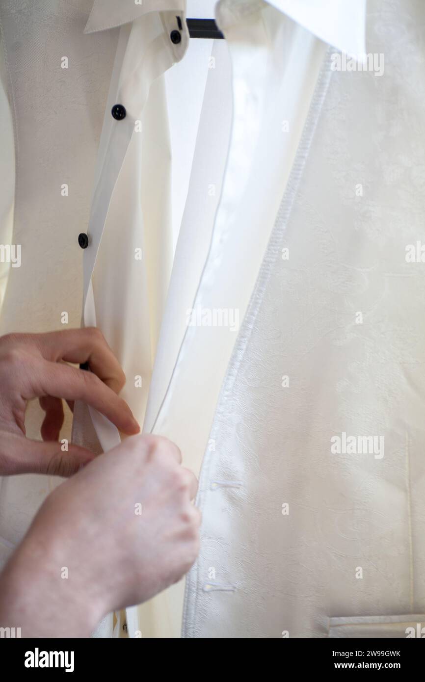 This photograph captures the meticulous process of a groom buttoning ...