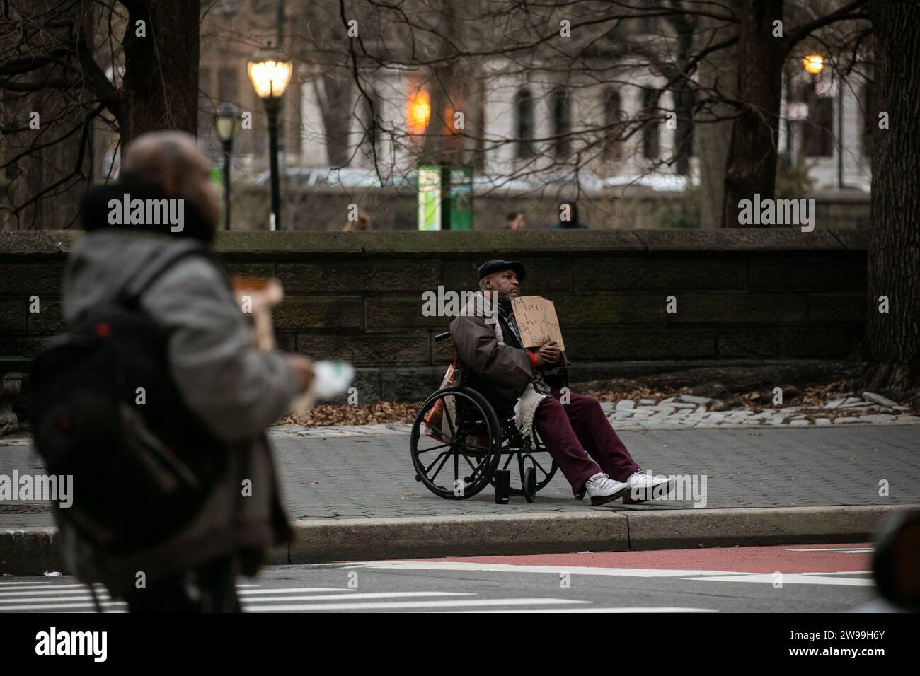 New York, USA. 24th Dec, 2023. A man in a wheelchair holds a cardboard ...