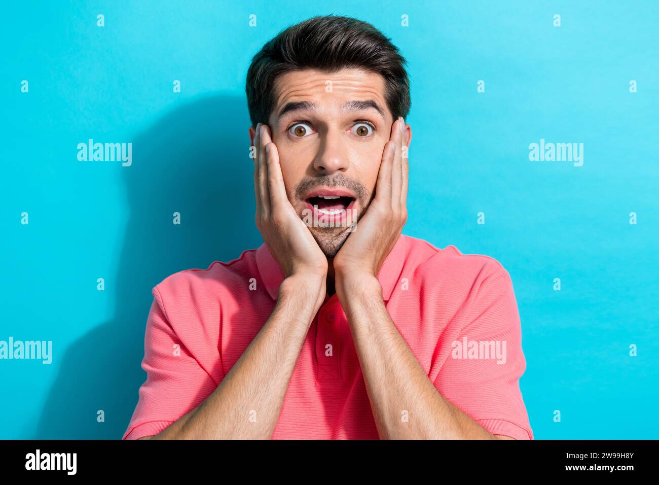 Portrait of young brunet hair guy hands cheeks confused open mouth ...