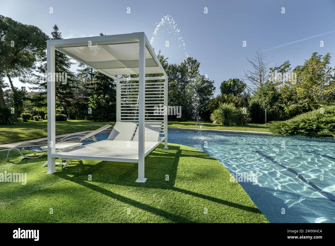 A white metal Balinese bed at the edge of a pool in a luxury estate ...