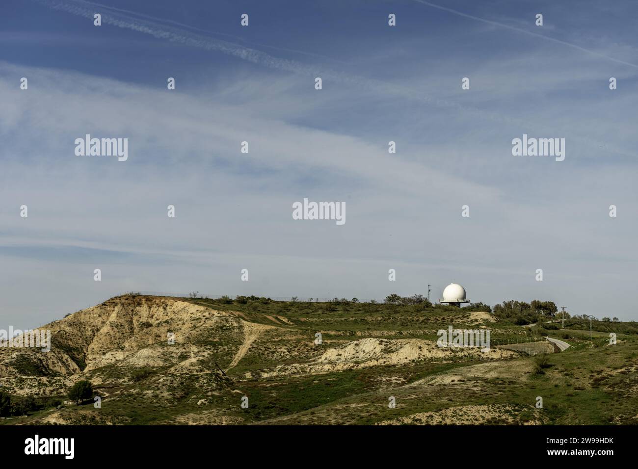 A hill with little vegetation and some small trees with an airport ...