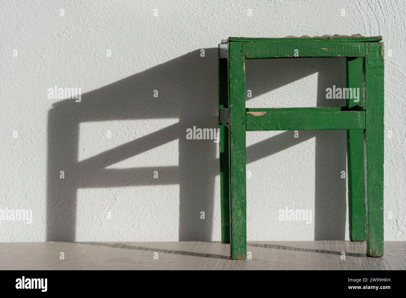 Green chair illumination on the white wall background. Light and shadow ...