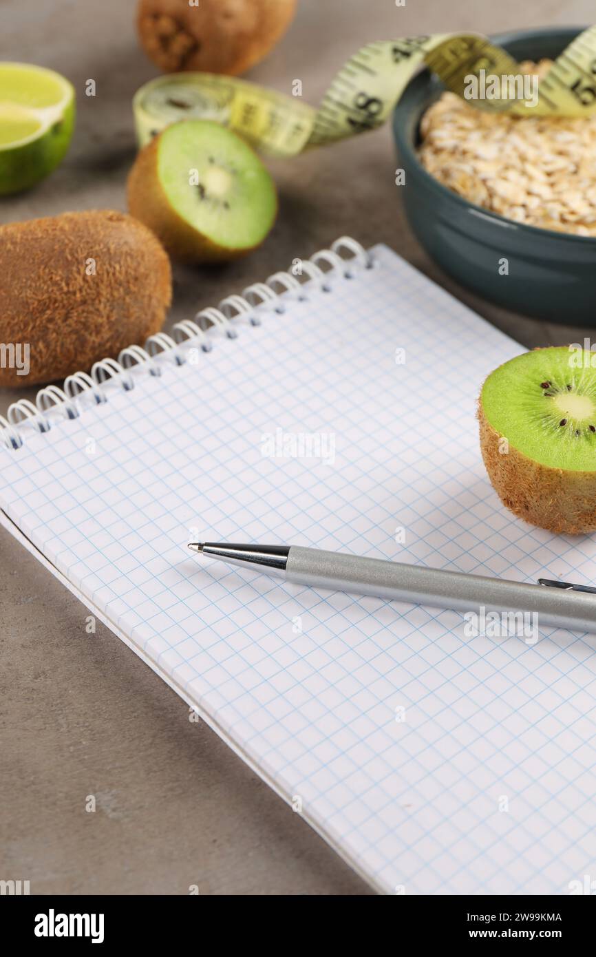 Healthy diet. Notebook, measuring tape, pen and products on grey table ...