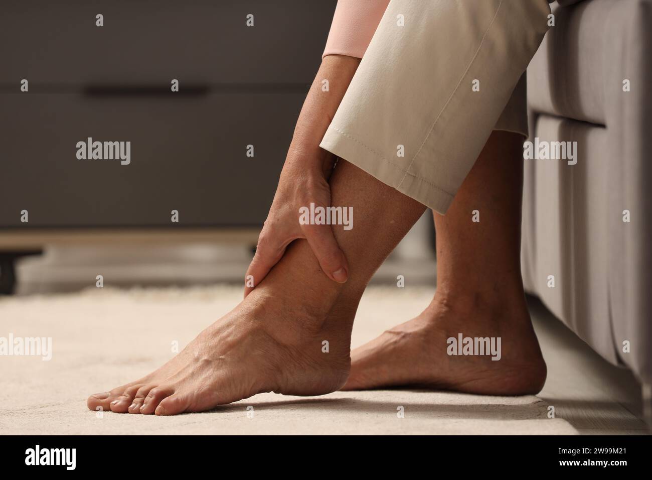 Mature woman suffering from pain in leg indoors, closeup. Rheumatism ...