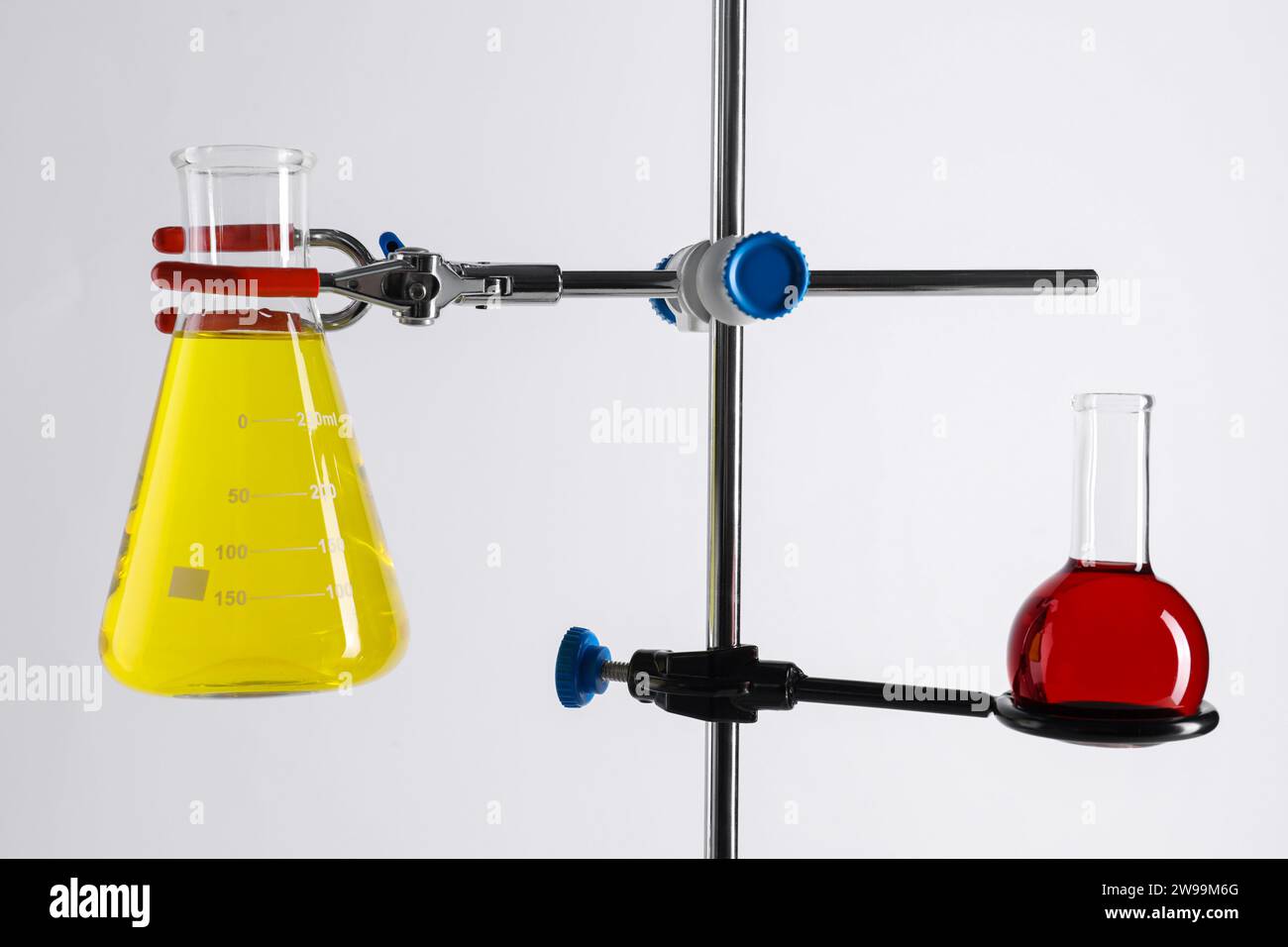 Retort stand and laboratory flasks with liquids on white background ...