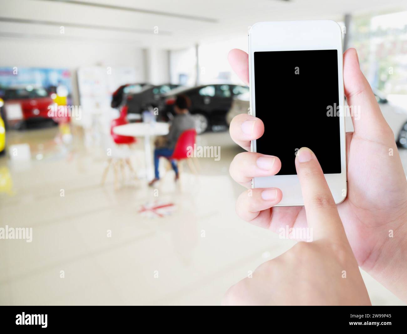 woman hands holding mobile phone with blurred background of new cars in ...