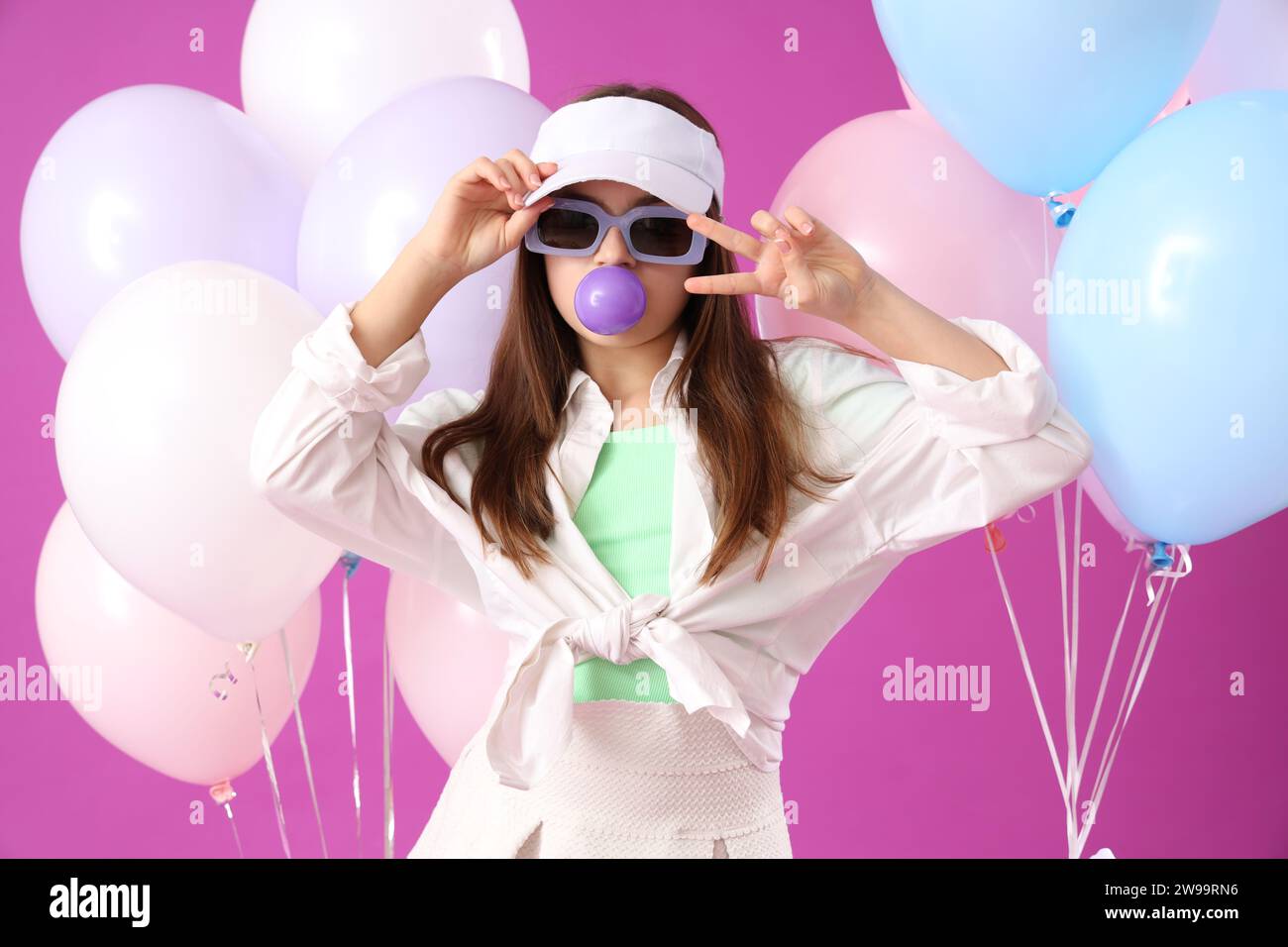 Trendy girl with balloons blowing bubble gum on purple background Stock ...