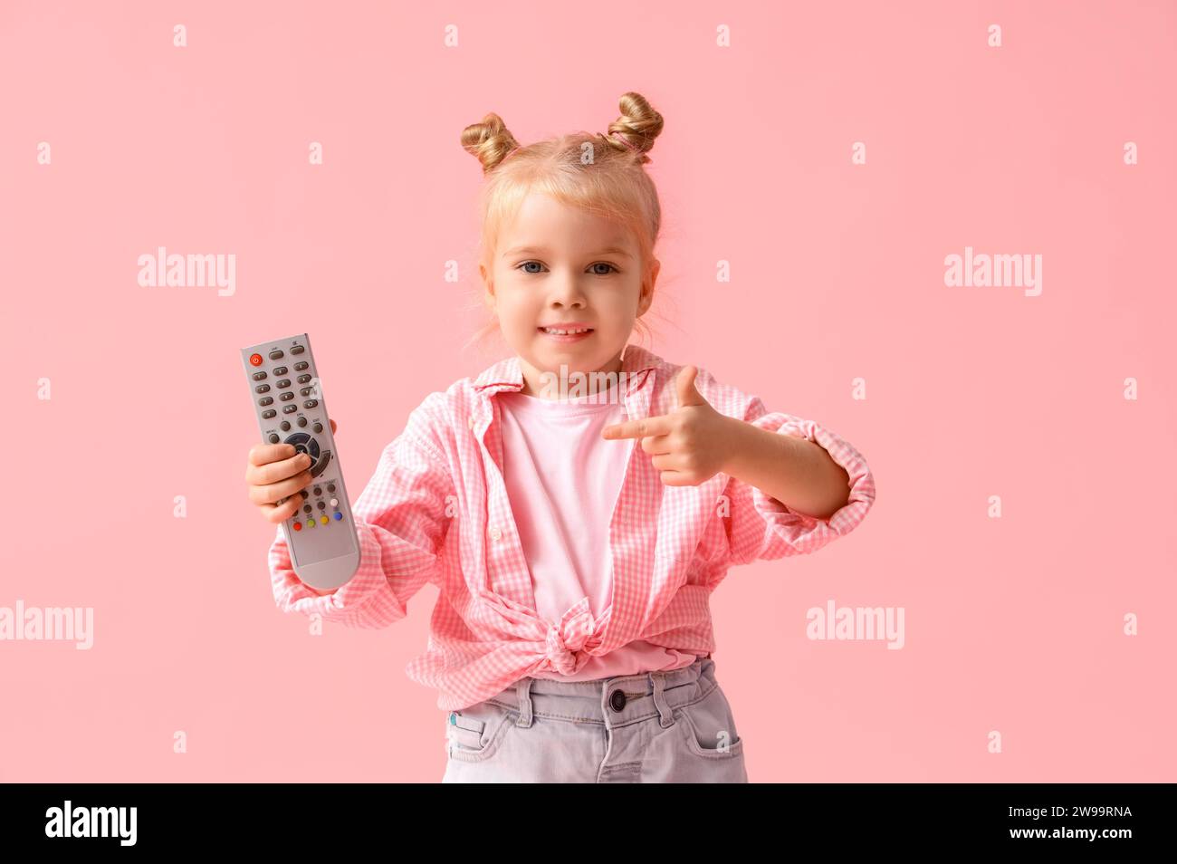 Little girl pointing at TV remote control on pink background Stock ...