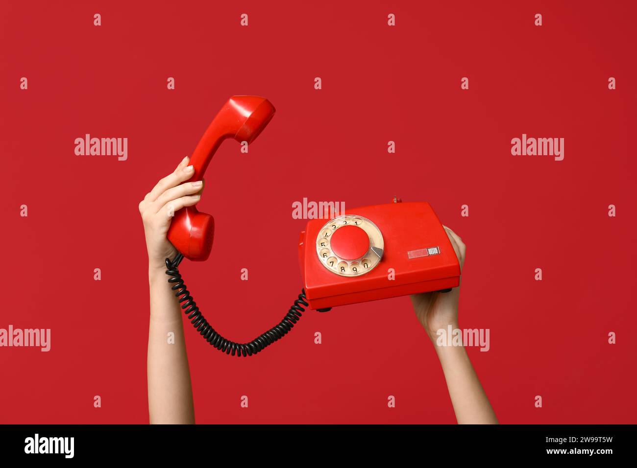 Female hands holding vintage telephone on red background. Valentine's ...