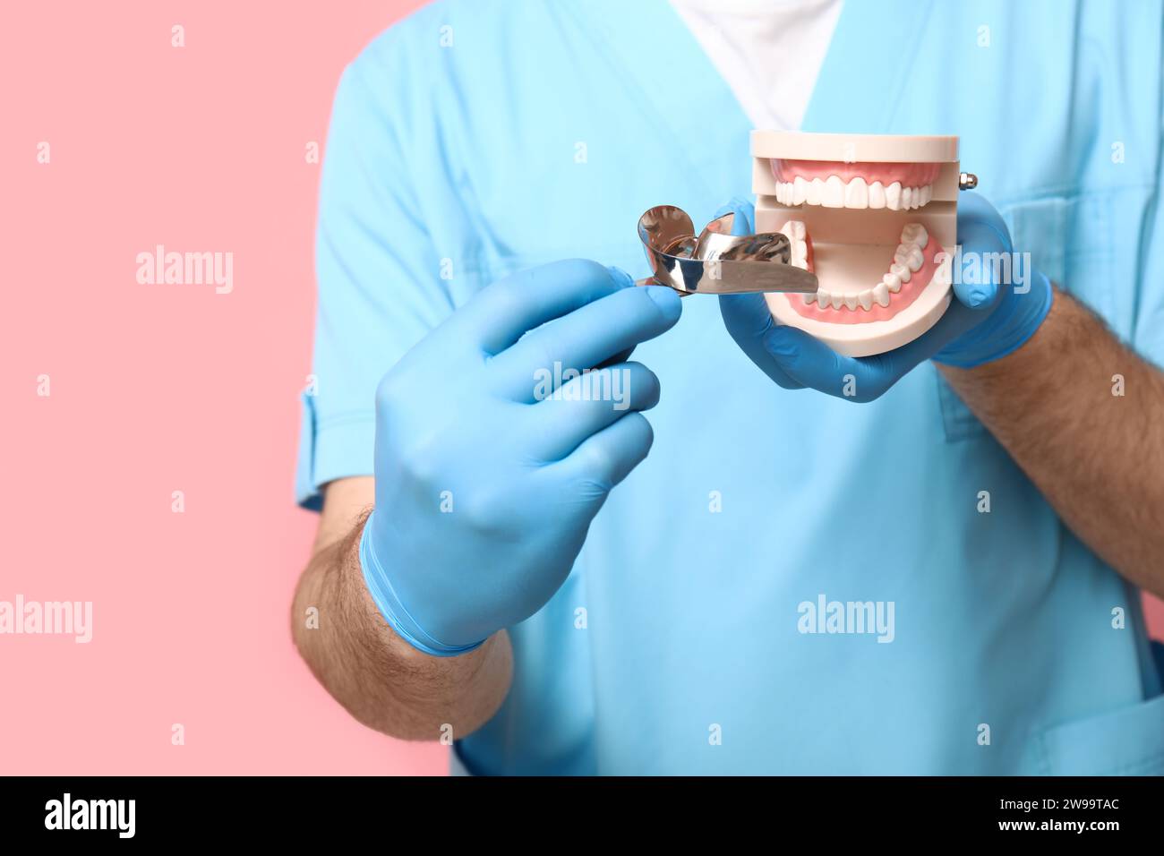 Male dentist with dental impression tray and jaw model on pink ...