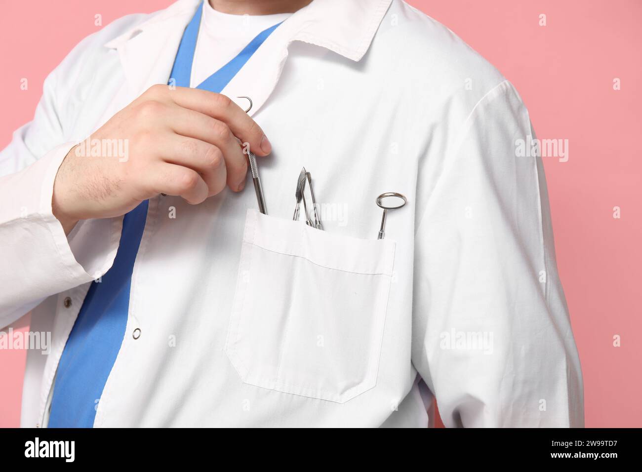 Dentist with dental tools in pocket on pink background, closeup. World ...